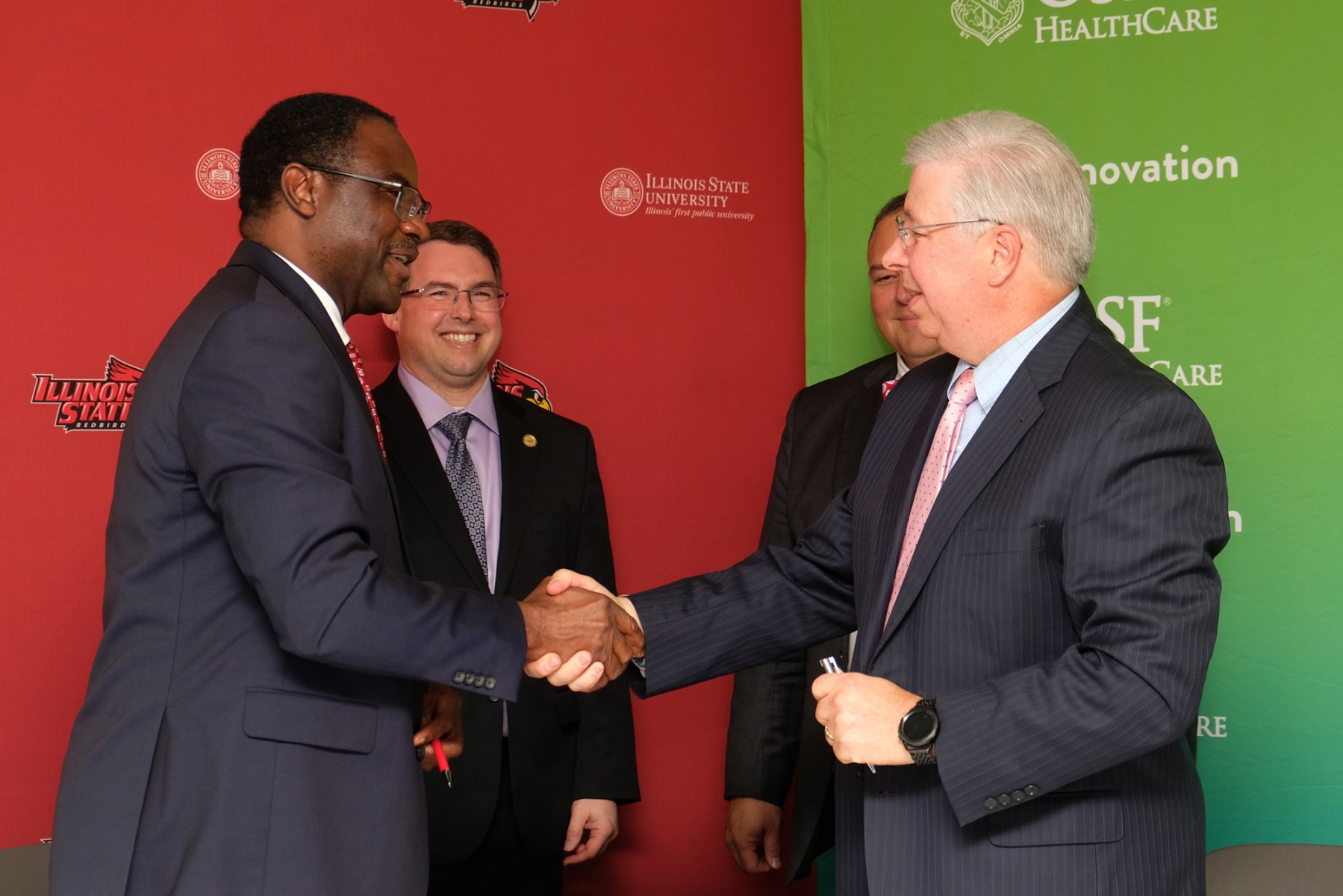 Tarhule and Sehring shake hands after signing