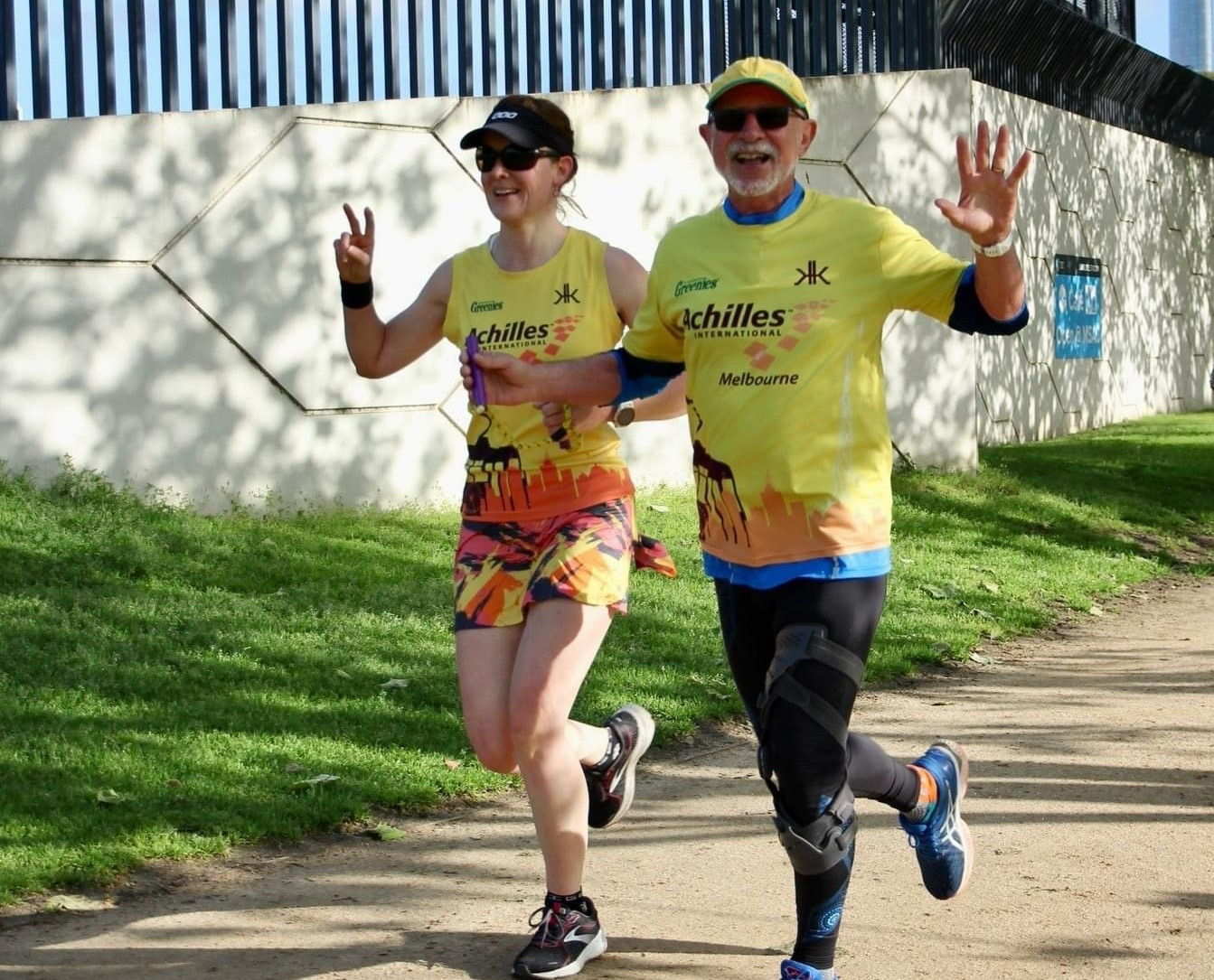 Natalie guiding Peter Symons, who are waving at the camera at Albert ...